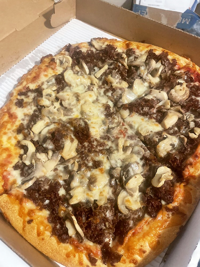Behold the legendary pizza cheesesteak in its natural habitat—where finely chopped steak and mushrooms mingle under a blanket of perfectly melted cheese.