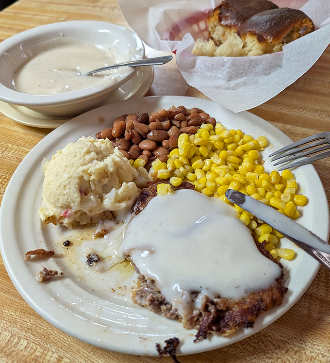 This chicken fried steak isn't just covered in gravy – it's swimming in a creamy ocean of Southern comfort with corn and beans standing guard.