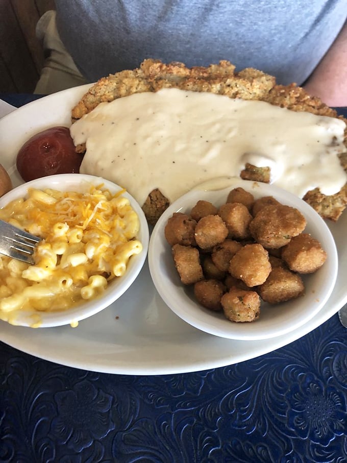 Behold the star of the show: golden-crusted chicken fried steak smothered in cream gravy, flanked by mac and cheese and fried okra.