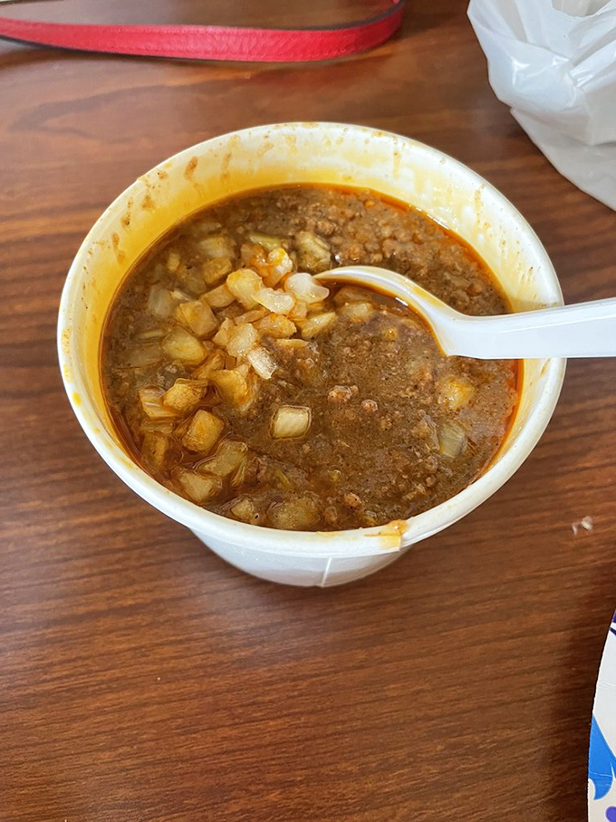 Cincinnati chili in its natural habitat—a simple bowl showcasing that distinctive sauce-like consistency with diced onions playing supporting roles.