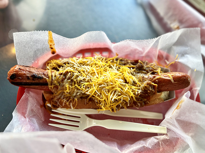 The star of the show in all its glory – a perfectly grilled dog smothered in homemade chili and blanketed with cheese.