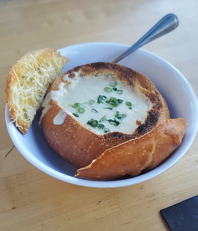 Bread bowl brilliance! This clam chowder isn't just served, it's presented—creamy, herb-flecked perfection nestled in a sourdough throne.