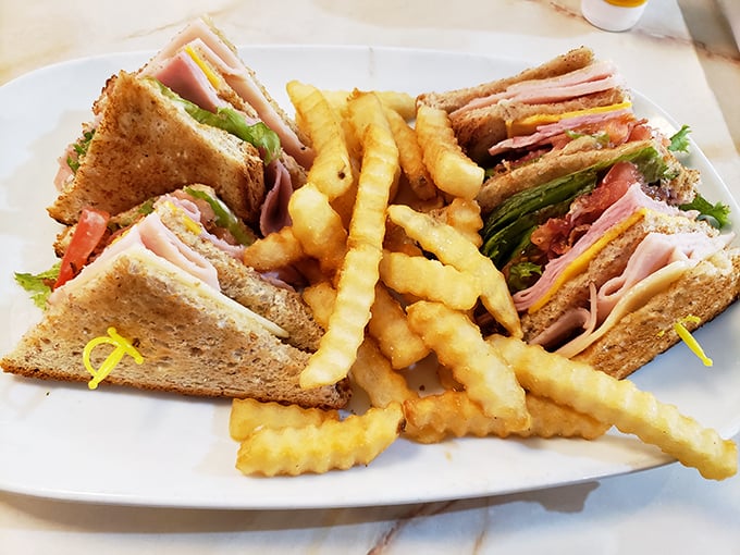 The club sandwich: architectural marvel of the culinary world. Those perfectly golden crinkle-cut fries aren't just sides—they're supporting actors deserving their own award.