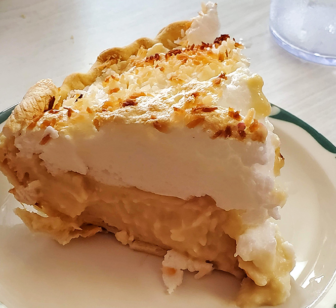The coconut cream pie stands tall and proud, its meringue peaks toasted to perfection—architecture so beautiful it deserves its own zip code.