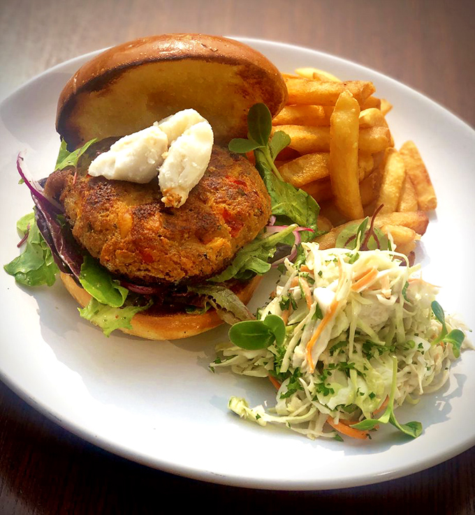 This isn't just a crab cake sandwich—it's edible architecture. Golden-brown perfection topped with creamy aioli and served with hand-cut fries and house slaw.