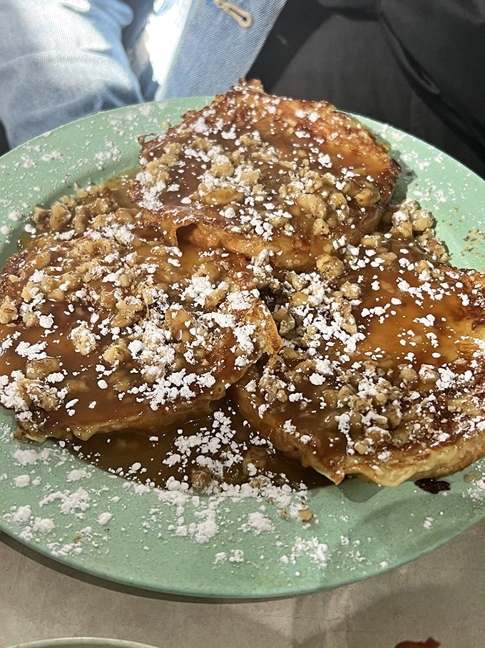 Behold the star attraction: croissant French toast dusted with powdered sugar and walnuts – architecture so beautiful, it deserves its own zip code.