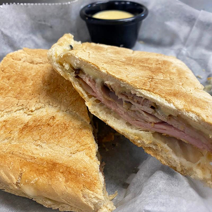 Behold the star of our show – a Cuban sandwich pressed to golden perfection, with layers that harmonize like a well-rehearsed doo-wop group.