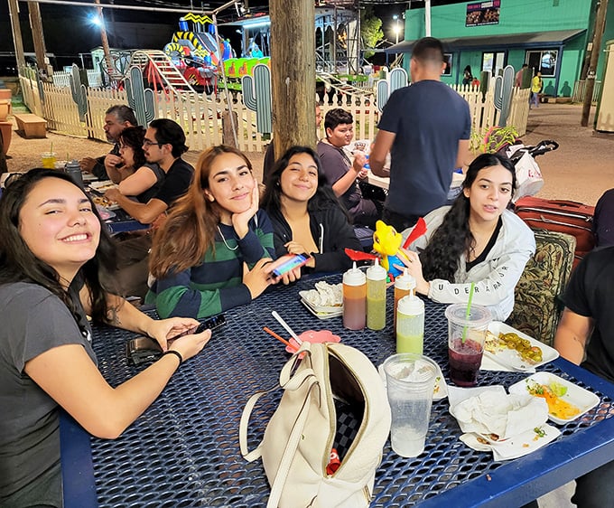 Nothing builds friendships like sharing street food at colorful tables—these smiling faces know the universal truth that the best conversations happen over good eats.