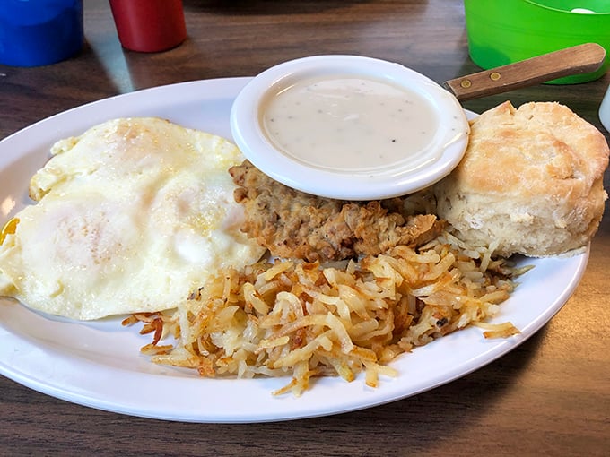 Breakfast perfection on a plate: sunny-side up eggs, crispy hash browns, and a biscuit that would make your grandmother both jealous and proud.