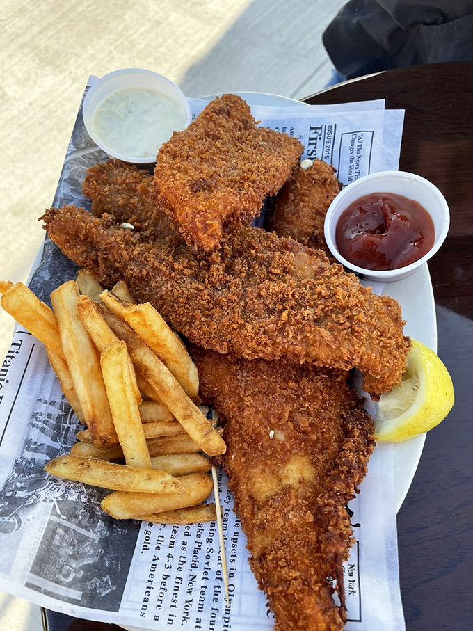 Golden-brown perfection on a plate! This crispy fish with hand-cut fries, accompanied by tartar and cocktail sauces, is the kind of dish worth crossing state lines for.