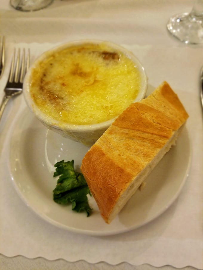 The French onion soup arrives like a work of art—that golden, bubbling cheese canopy hiding a savory treasure of caramelized onions below.