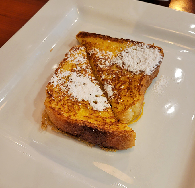 French toast that's dressed better than most people at breakfast—powdered sugar as delicate as first snow on golden, crispy bread.