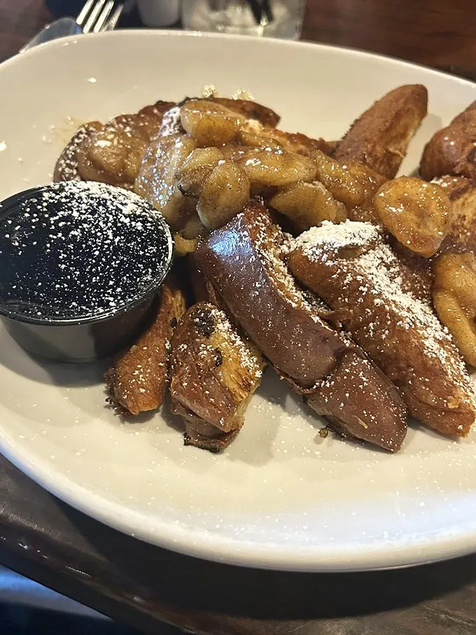 French toast that deserves its own thank-you note. Perfectly caramelized with apple topping and a dusting of powdered sugar—breakfast transcends into dessert territory without apology.