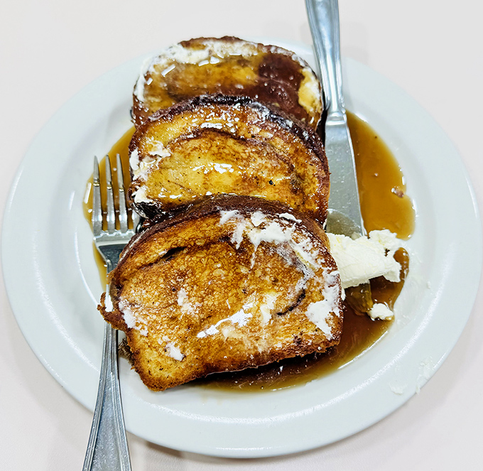 The legendary French toast in all its glory—golden-brown perfection with a dusting of powdered sugar that makes breakfast feel like a celebration.