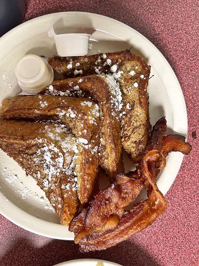 Golden-brown French toast dusted with powdered sugar and flanked by perfectly crisp bacon - breakfast's greatest hits on a single plate.