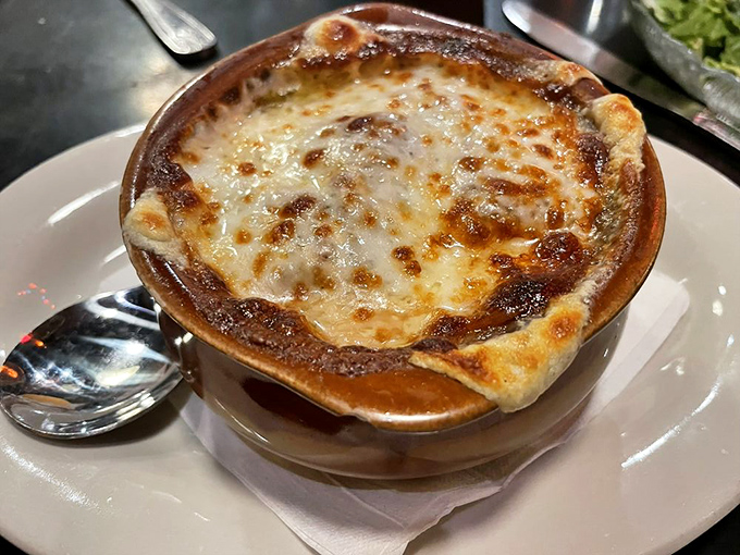 This isn't just French Onion Soup—it's a bubbling cauldron of comfort topped with a golden crown of melted cheese that stretches with each glorious spoonful.