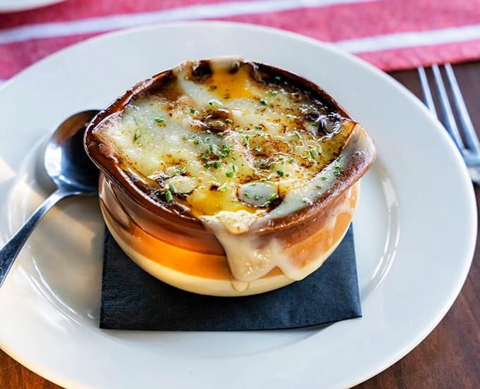 The French onion soup arrives like a work of art – that glorious moment when the broiled cheese stretches between spoon and crock is worth the trip alone.