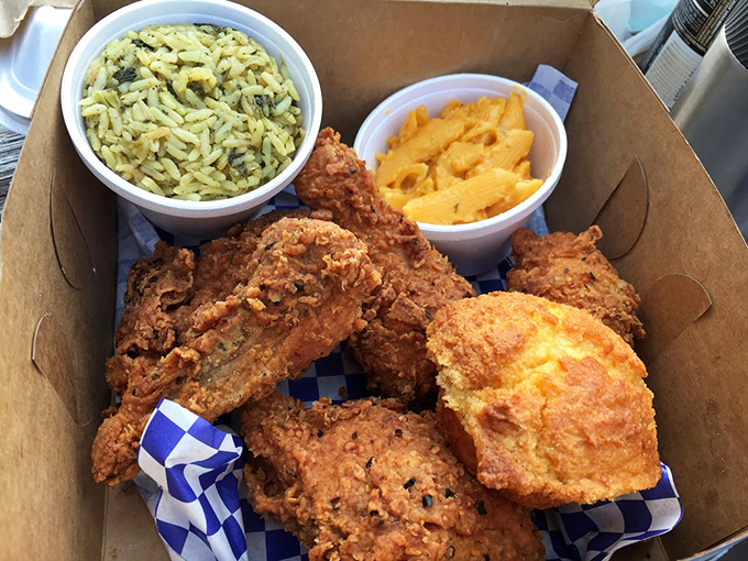 Golden-brown perfection in a box. That crust shatters with each bite, revealing juicy meat beneath, while mac and cheese and seasoned rice stand ready as worthy sidekicks.