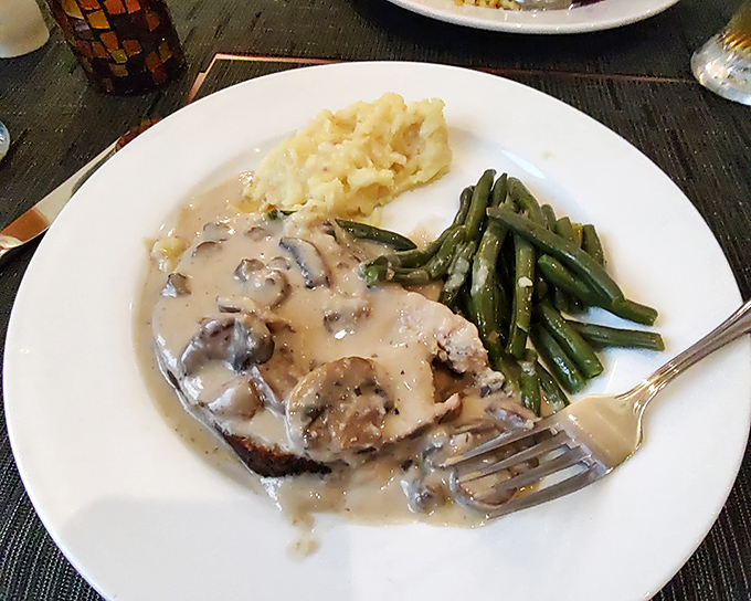 The famous German meatloaf arrives like royalty, draped in mushroom sauce. Those mashed potatoes and green beans aren't just sides—they're loyal subjects.