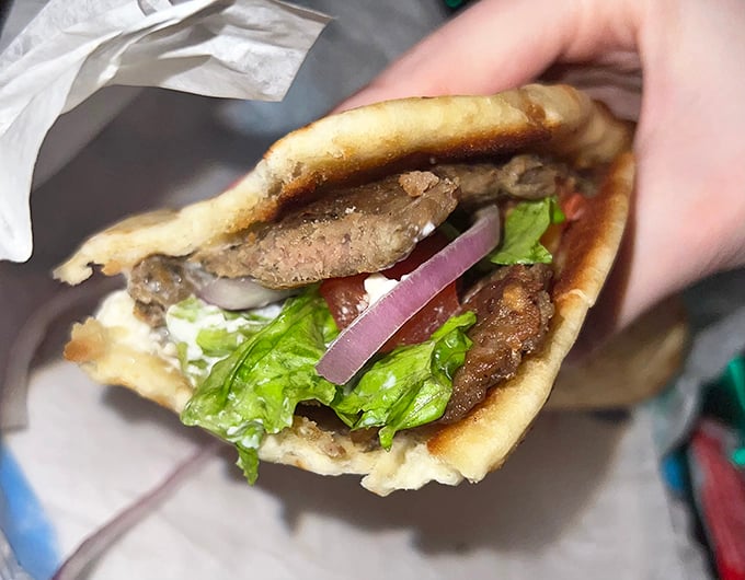 The legendary gyro in all its glory—a perfect harmony of seasoned meat, fresh veggies, and tzatziki sauce. This isn't fast food; it's slow food done quickly.