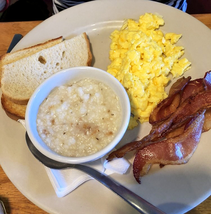Breakfast perfection doesn't need fancy plating—just perfectly scrambled eggs, crispy bacon, creamy grits, and toast waiting for its butter baptism.