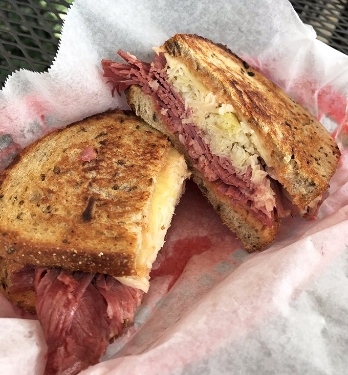 Behold the Reuben in its natural habitat—perfectly grilled rye, corned beef stacked with ambition, and sauerkraut that means business.