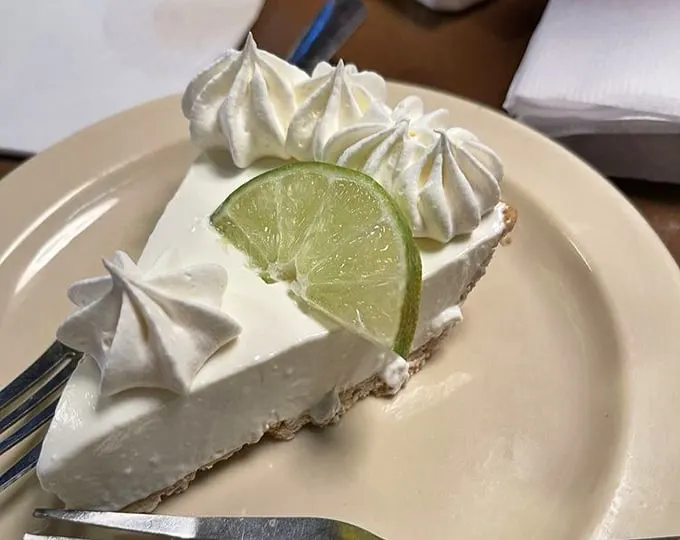 Key lime pie that strikes the perfect balance between sweet and tart—topped with whipped cream rosettes that practically demand a moment of silence.