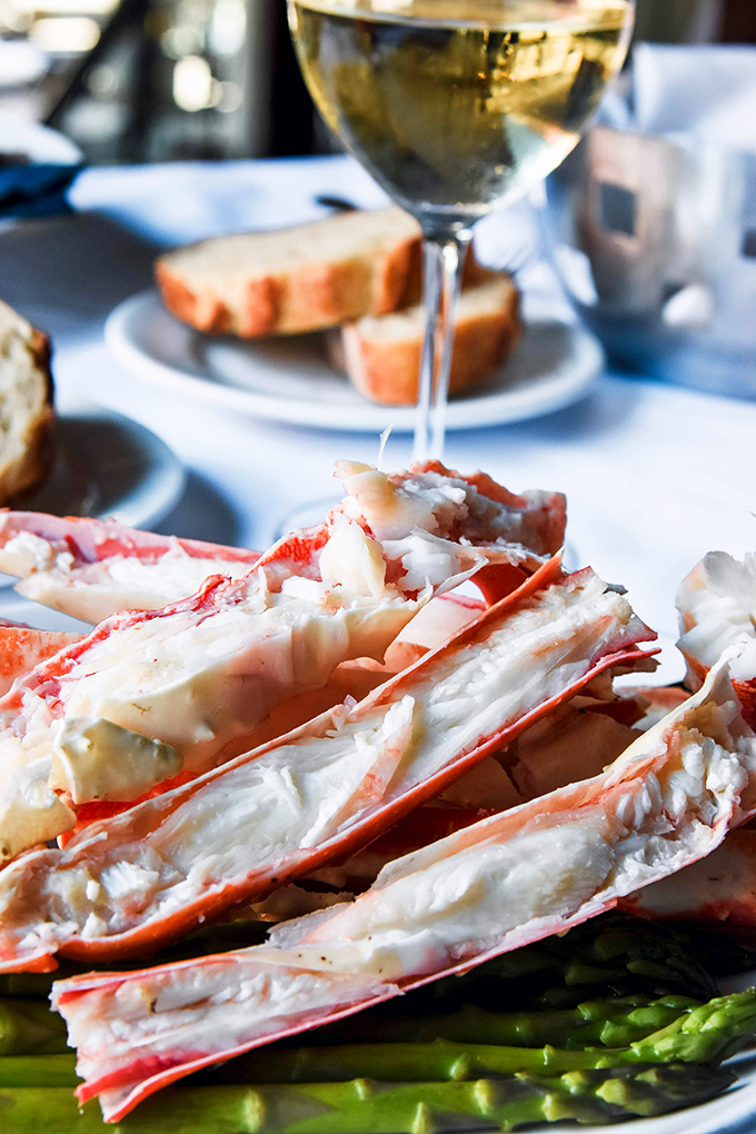 These split king crab legs aren't just dinner—they're edible architecture. Sweet meat glistening with butter, poised atop vibrant asparagus spears like nature's perfect scaffold.