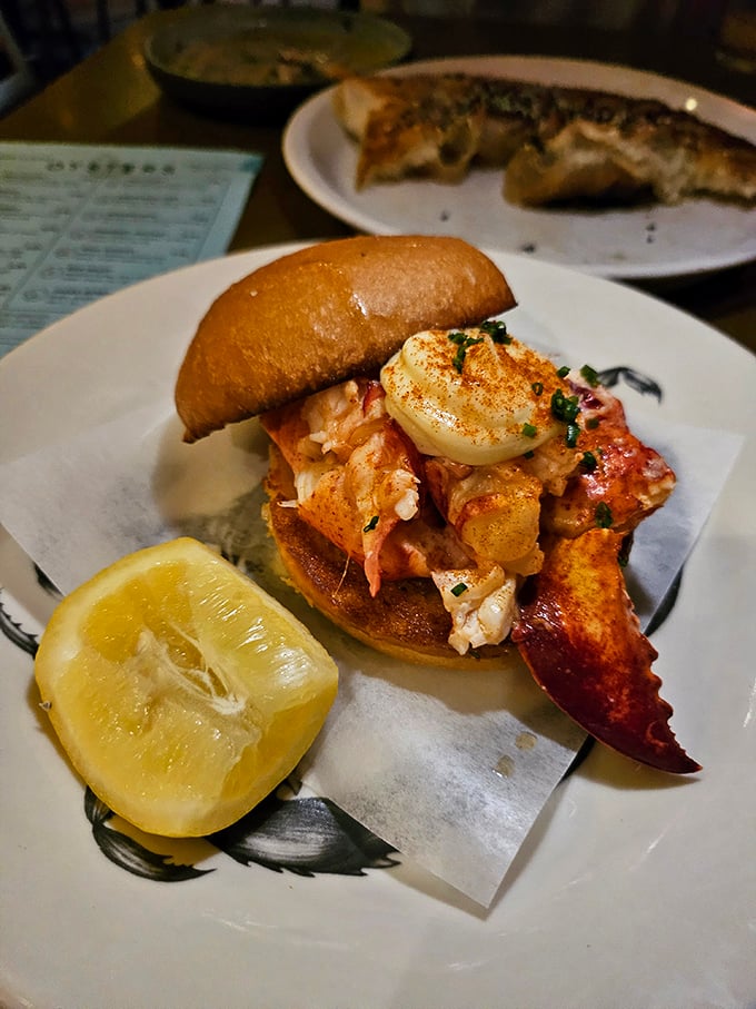 The legendary lobster roll arrives like Neptune's gift—chunks of sweet meat barely contained by a toasted bun, with a claw dramatically announcing its presence.