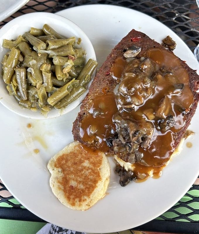 That meatloaf isn't just dinner, it's an event – crowned with savory gravy and flanked by green beans that didn't escape their bacon destiny.