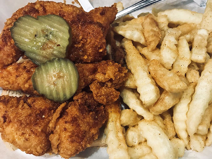 Golden-brown tenders with pickle coins standing guard over a mountain of crinkle-cut fries—comfort food that's dressed for a spicy occasion.
