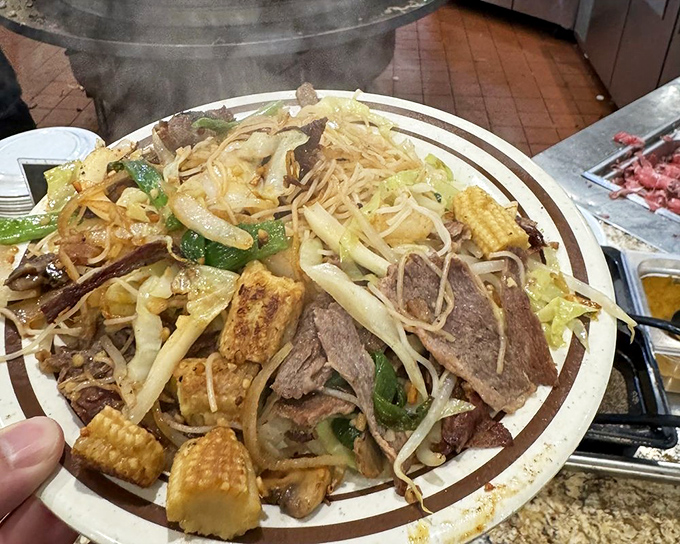 A mountain of noodles, vegetables, and protein creates a symphony of textures in this Mongolian BBQ plate – proof that sometimes more is definitely more.
