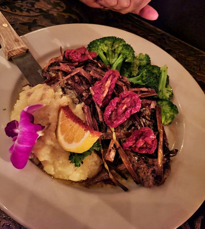 A perfectly seared steak arrives like edible artwork—mashed potatoes as the canvas, crisp broccoli for color, and those vibrant garnishes adding the final masterful touch.