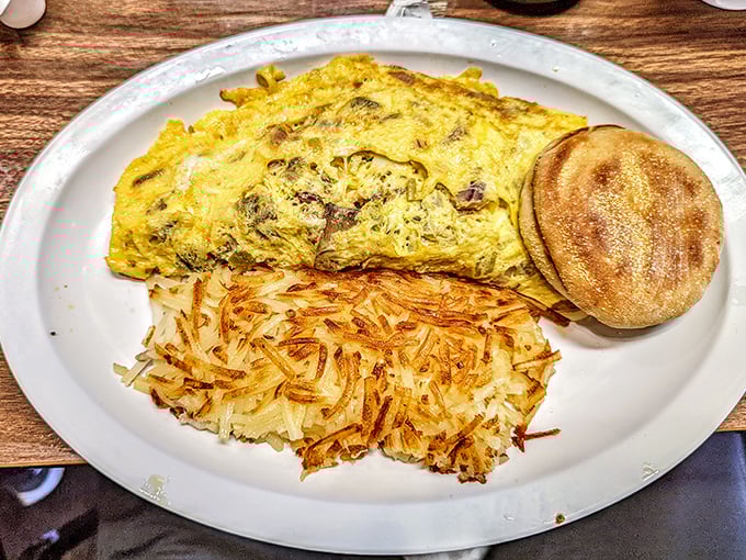 Behold the omelet in its natural habitat—perfectly folded, generously stuffed, and flanked by golden hash browns and an English muffin.