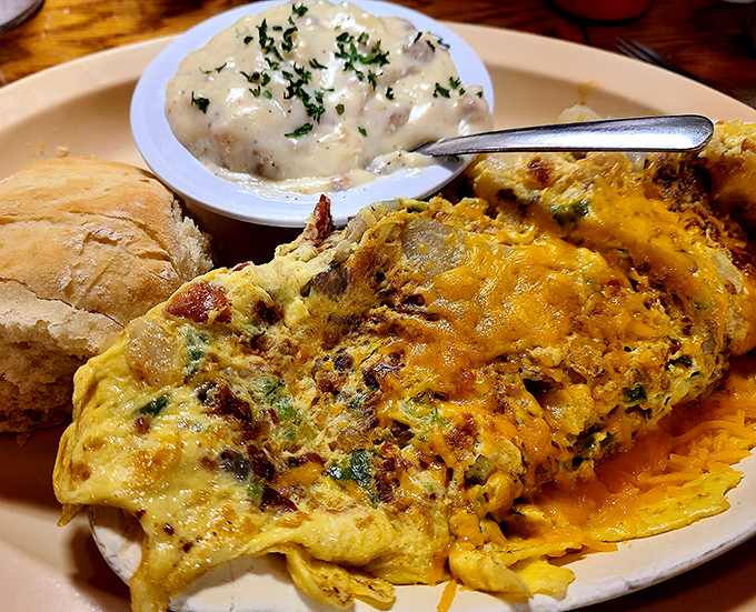 Behold the omelet in its natural habitat—perfectly folded, generously stuffed, and accompanied by a side of gravy that's practically begging for a biscuit.