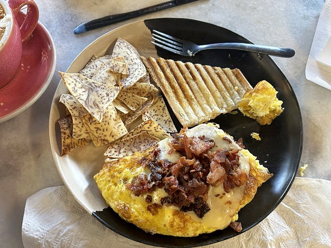 The legendary omelet in all its glory – fluffy eggs embracing a melty cheese blanket and bacon confetti. Breakfast architecture at its finest.