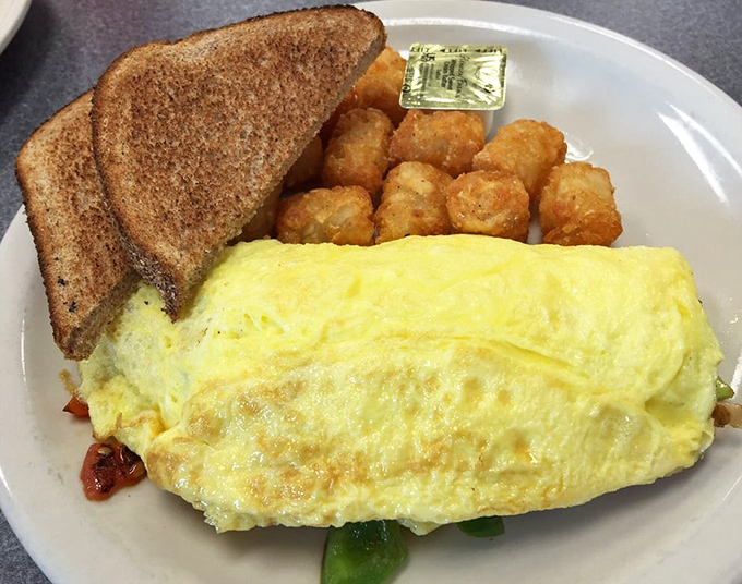 This omelet doesn't just arrive on your plate—it makes an entrance, fluffy and proud, with perfectly golden hash browns standing guard.