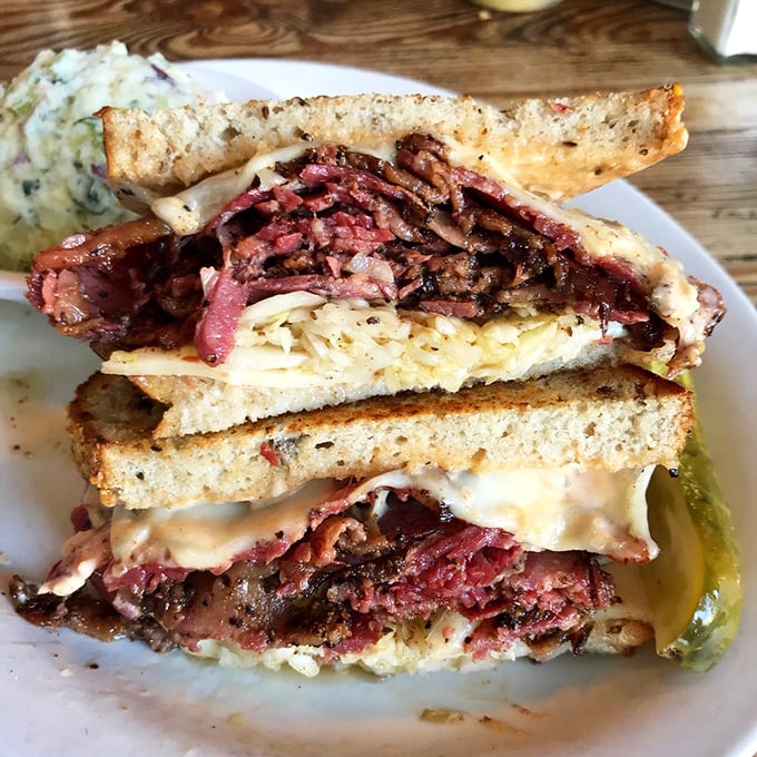 Behold the architectural marvel that is the pastrami sandwich – a skyscraper of meat that demands both hands and your full attention.