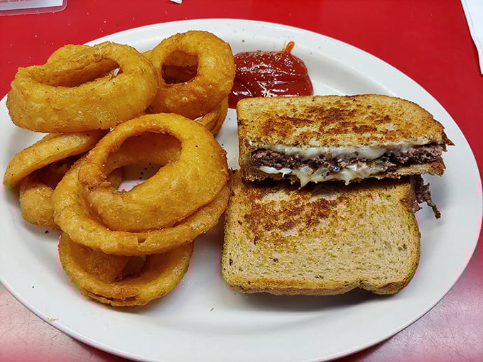 Golden onion rings that crunch like autumn leaves alongside a patty melt that would make your cardiologist wince but your taste buds applaud.