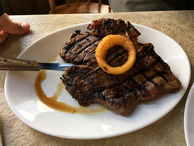 That steak isn't just dinner; it's a religious experience with grill marks. The onion ring crown is a nice touch—every protein deserves proper regalia.