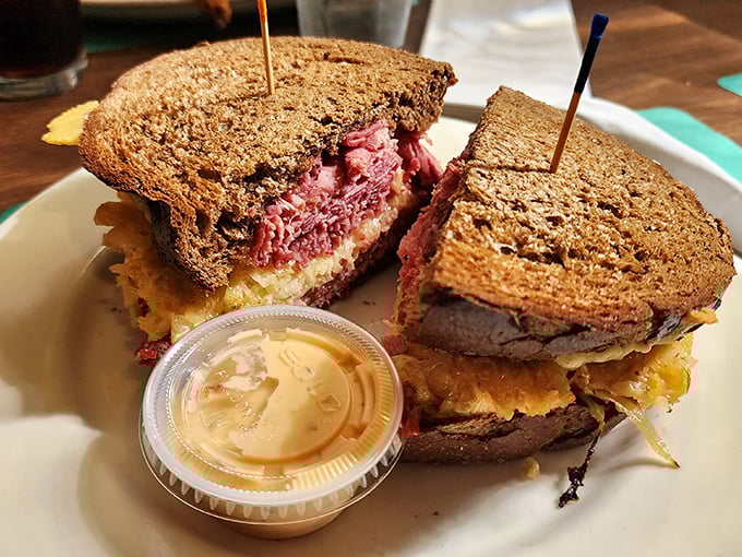 The legendary Reuben in all its glory – a skyscraper of corned beef requiring both hands, engineering skills, and absolutely zero concern for your shirt's cleanliness. 