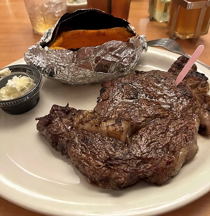 This isn't just a ribeye; it's a masterpiece of marbling that makes carnivores weak at the knees. The foil-wrapped potato stands ready for backup.