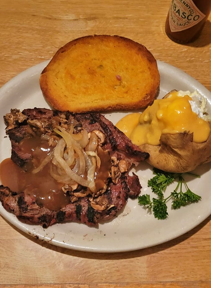 Behold the star of the show: a perfectly seared ribeye with grilled onions, cheese-loaded baked potato, and that famous cheese toast. Napkins required.