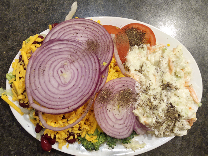 A salad bar masterpiece that would make any buffet enthusiast weak at the knees—those purple onion rings are practically jewelry for your lettuce.