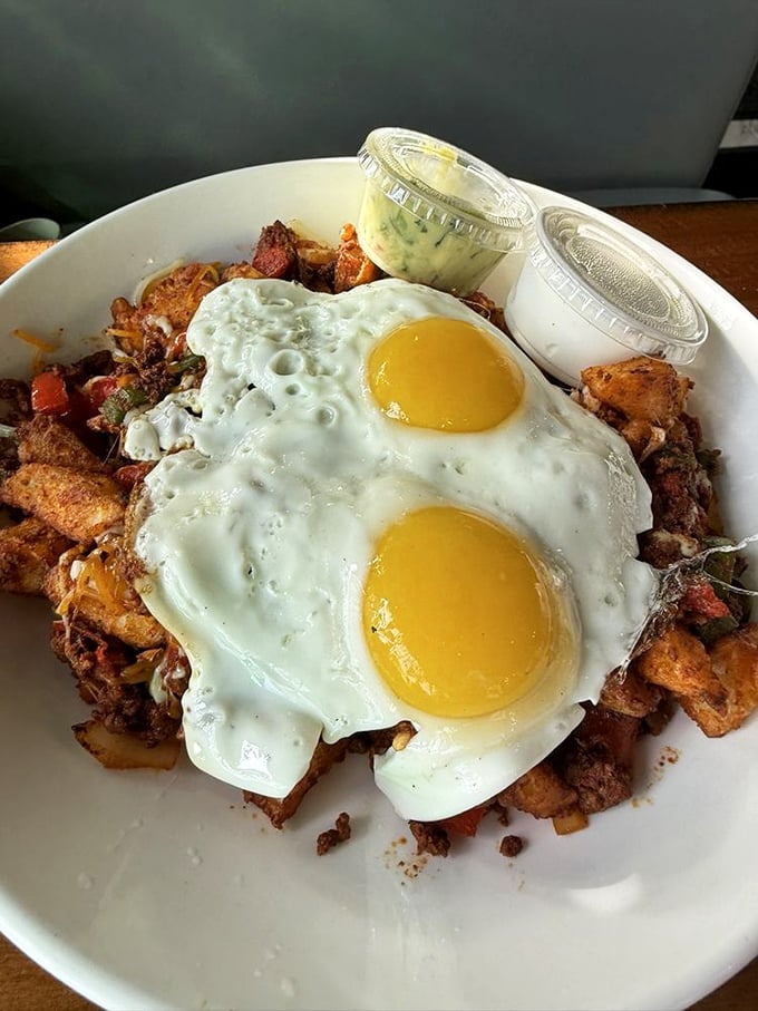 Behold the skillet in all its glory—two sunny-side-up eggs crowning a kingdom of crispy potatoes and savory treasures below. Morning royalty, served.