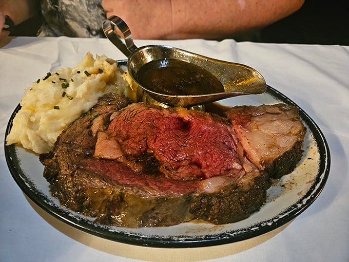 Behold the prime rib in its natural habitat—perfectly pink, swimming in au jus, with mashed potatoes standing guard. Meat poetry on a plate.