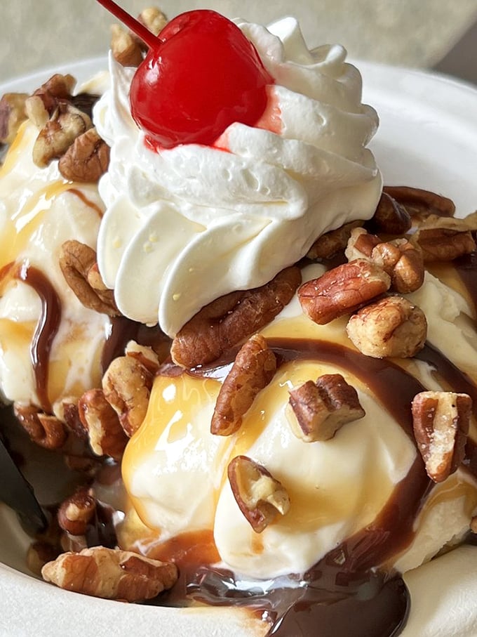 Caramel cascades over vanilla ice cream like a sweet waterfall, while pecans stand guard. This isn't just dessert—it's architecture.