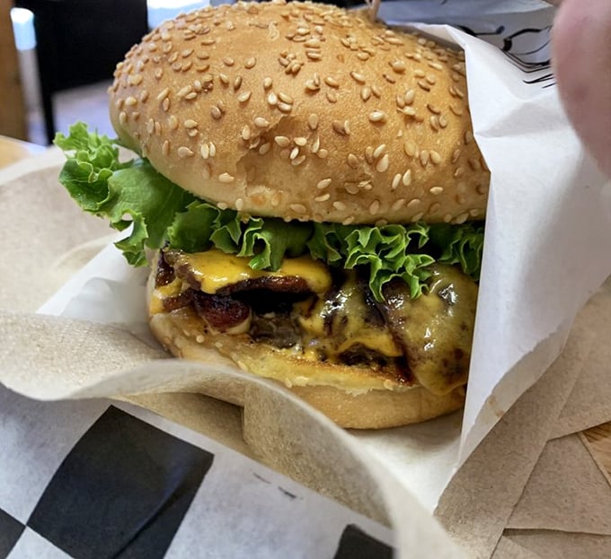 This isn't just a burger; it's edible architecture—a masterpiece of melted cheese, fresh lettuce, and a sesame-studded crown fit for royalty.