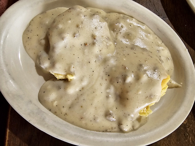 Biscuits and gravy done right – fluffy pillows drowning in creamy, peppery heaven that soothes souls.