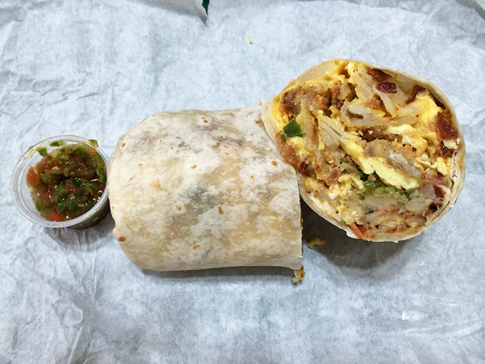 Behold the legendary breakfast burrito in all its glory—eggs, potatoes, cheese, and meat wrapped in tortilla perfection, with that famous salsa standing guard.
